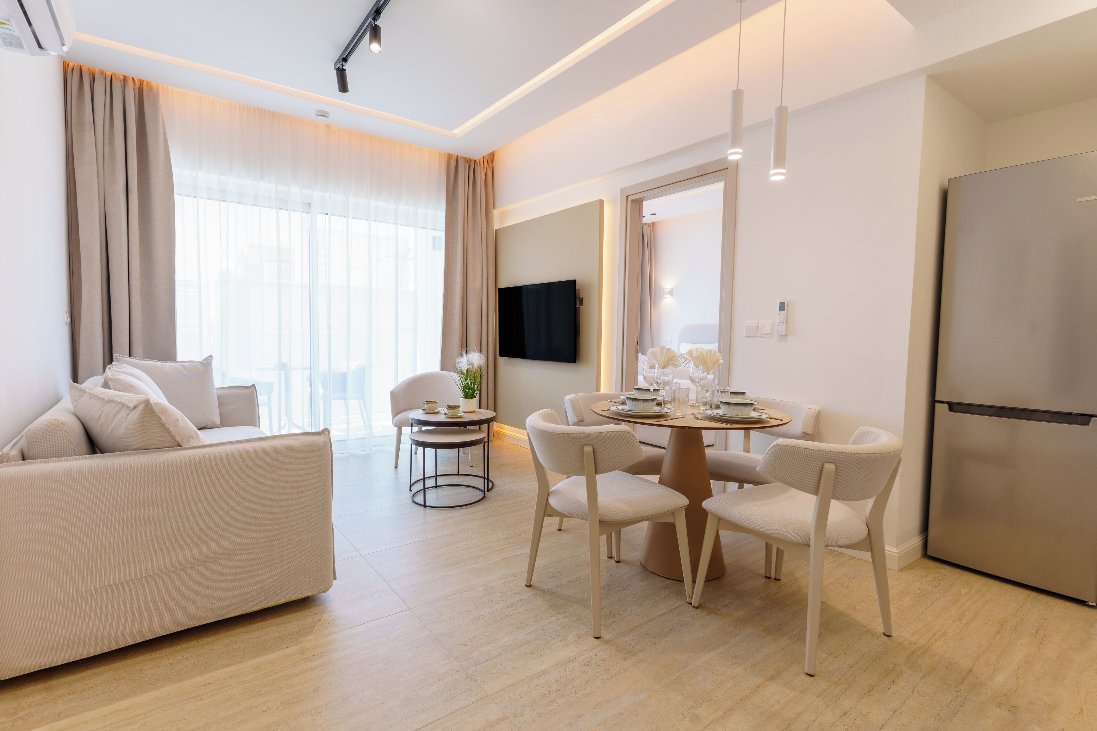 Uma sala de estar moderna com sofá, mesa de jantar, cadeiras e televisão de tela plana.