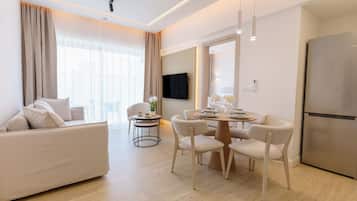 Uma sala de estar moderna com sofá, mesa de jantar, cadeiras e televisão de tela plana.