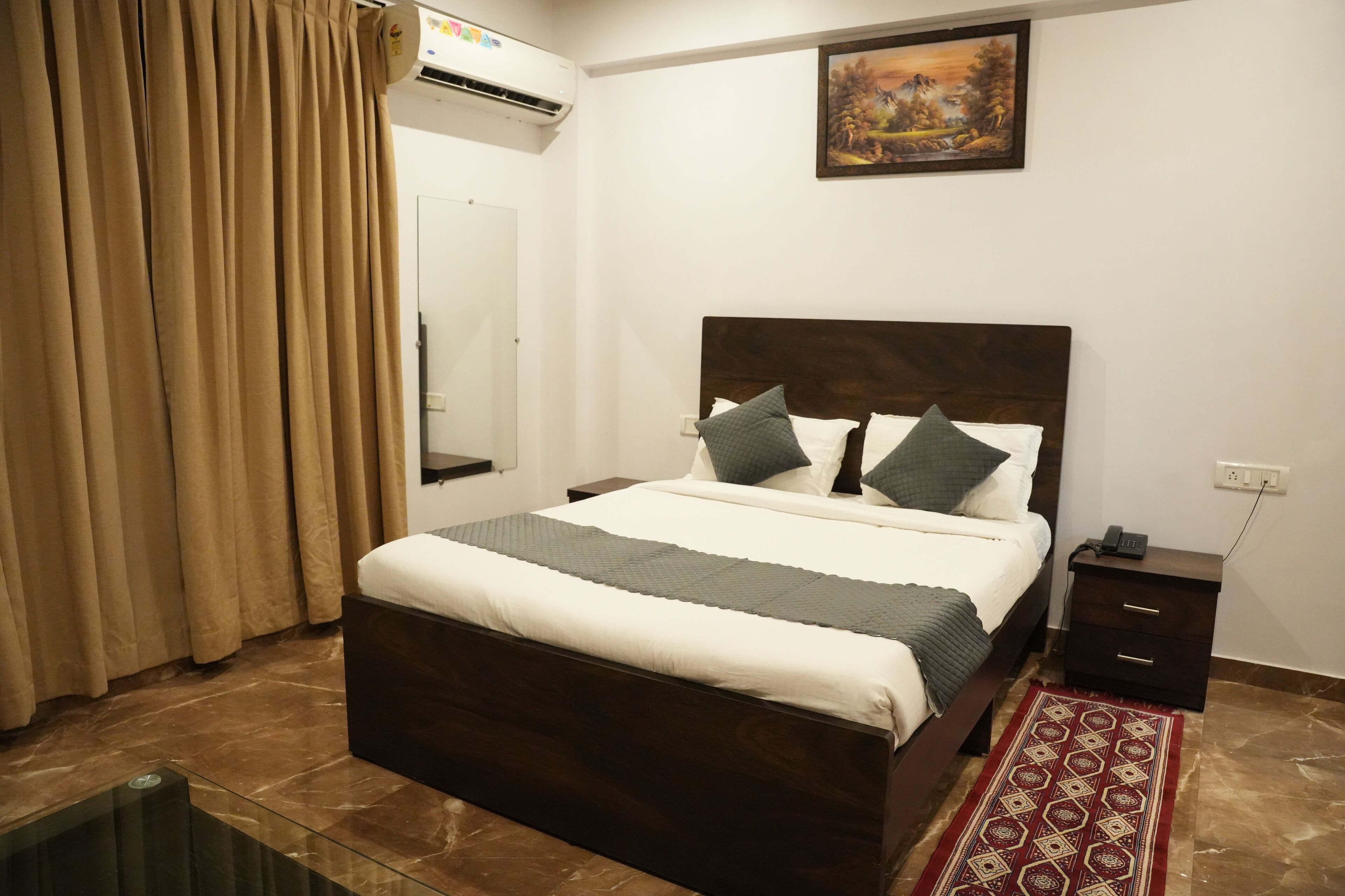 Quarto bem arrumado com uma cama grande, mesa de cabeceira, ar condicionado fixado na parede e um quadro na parede.