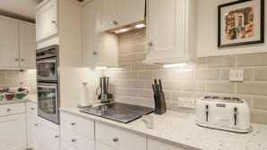 Cozinha moderna com armários brancos, forno embutido, torradeira Breville e painel de azulejos.