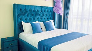 Quarto com uma cama grande, uma mesa de cabeceira e um dossel roxo.