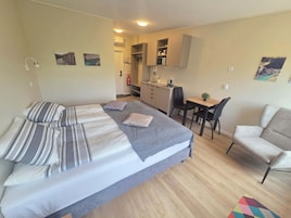 Quarto com cama, mesas de cabeceira, escrivaninha e uma cadeira.