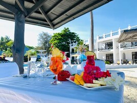 Uma mesa posta com uma bebida tropical, frutas e um copo.