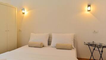 Quarto com cama, duas mesas de cabeceira, guarda-roupa e luzes fixadas na parede.