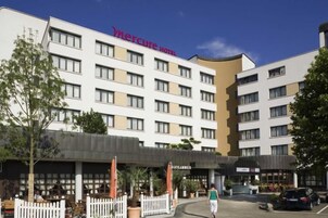 Um hotel com fachada branca, várias janelas e uma placa com a inscrição 'Mercure Hotel'.
