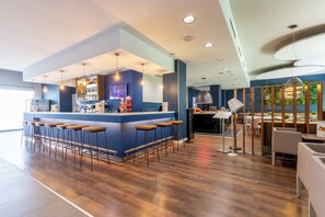 Uma área de bar moderna com parede azul decorativa, banquetas de madeira e um balcão com cardápio.