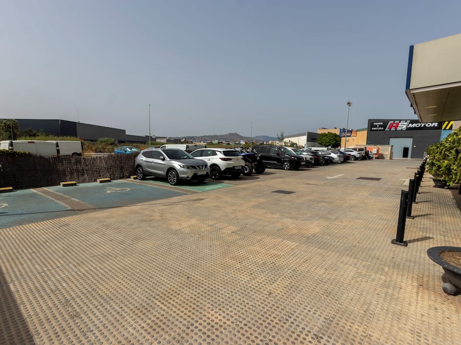 Um estacionamento com vários carros e um edifício com uma placa que diz 'RS MOTOR'.