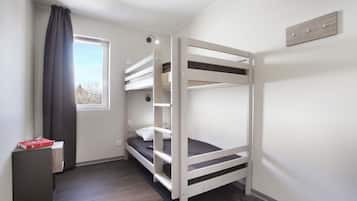 Quarto com beliche, uma escrivaninha e luminária fixa na parede.
