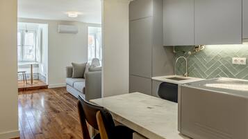 Uma cozinha moderna com armários cinza, bancada de mármore e backsplash em padrão herringbone.