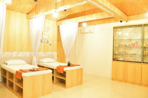 Um quarto de spa com duas camas, uma vitrine de vidro com produtos e painéis de madeira.