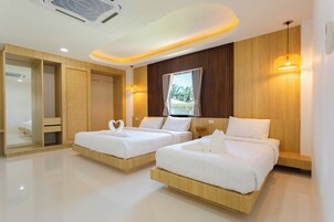 Quarto de hotel com duas camas, um espelho grande, painéis de madeira e uma janela com cortinas.