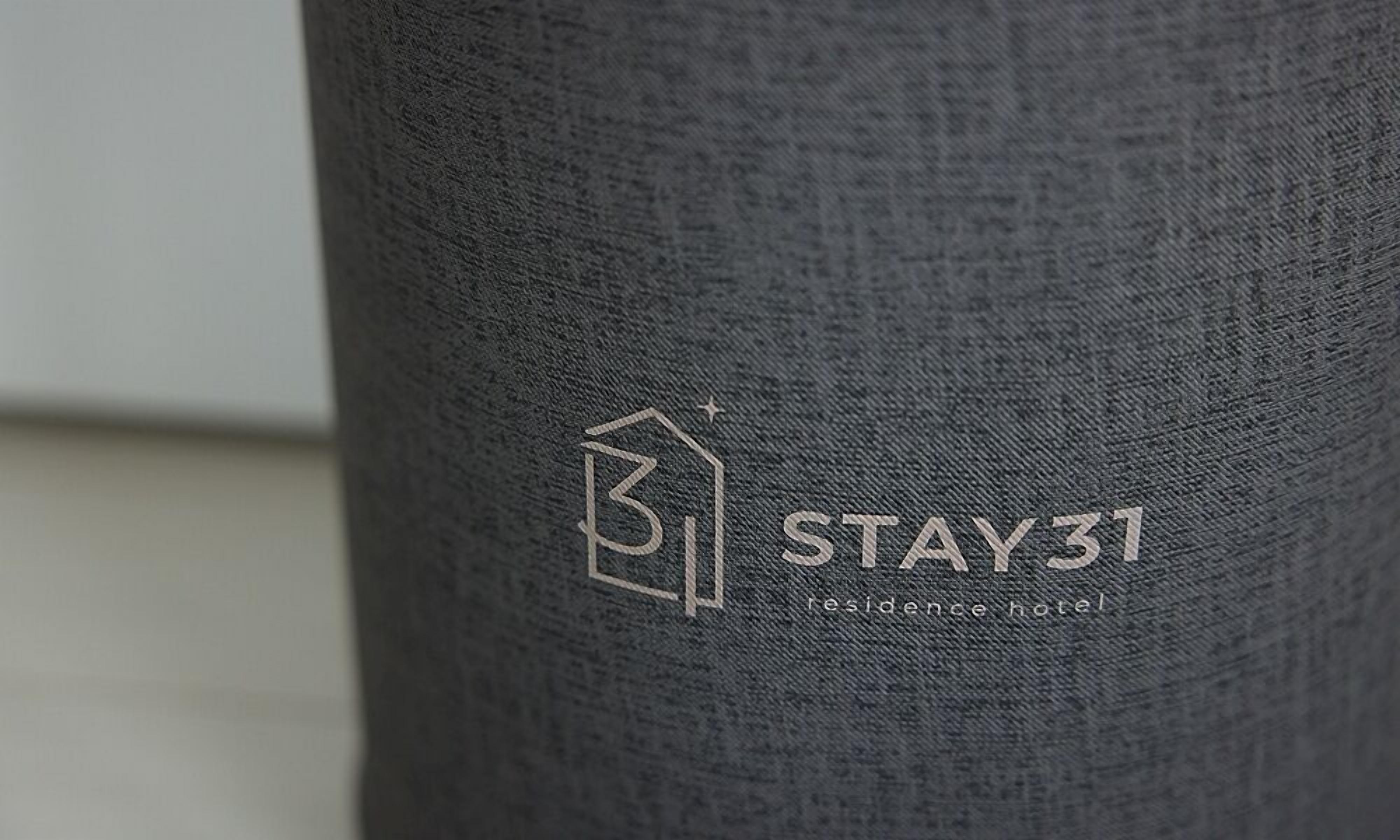 Tecido cinza texturizado com um logotipo e texto que diz “STAY 31 residence hotel”.