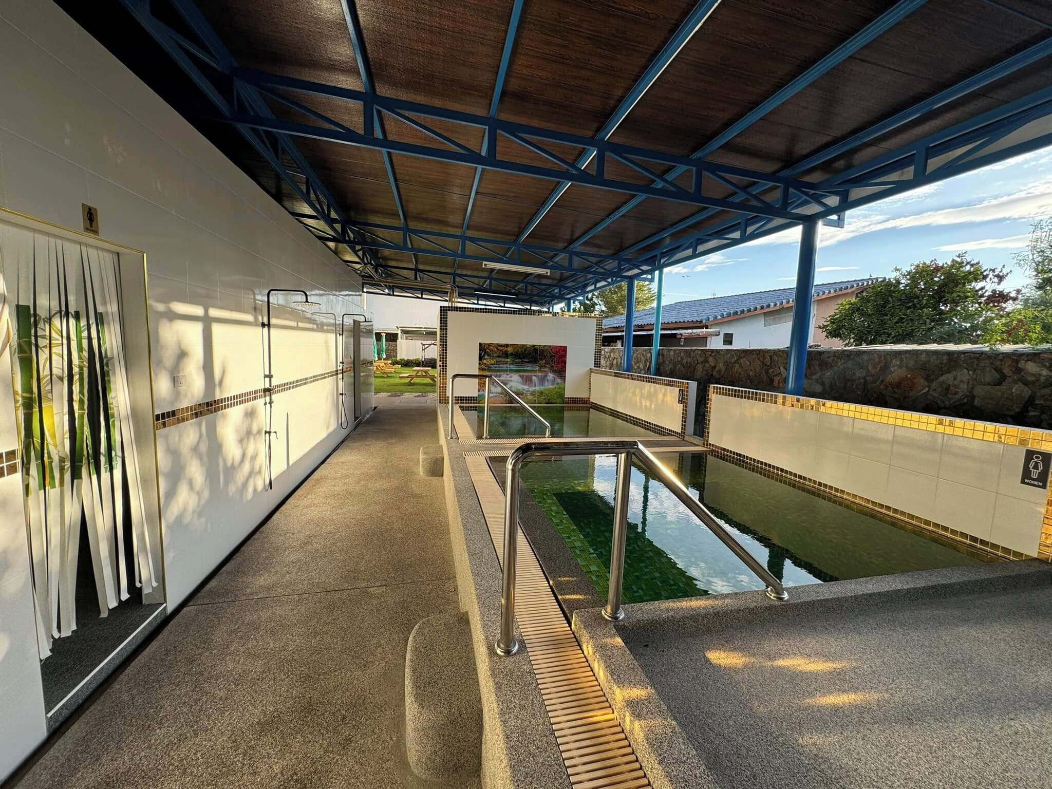 Uma área de piscina coberta com um deck ladrilhado, um espelho d'água e uma parede de pedra.