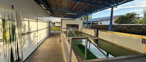 Uma área de piscina coberta com um deck ladrilhado, um espelho d'água e uma parede de pedra.