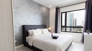 Quarto de hotel moderno com uma cama grande, vista para a cidade e uma parede cinza texturizada.