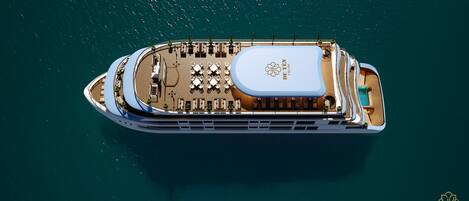 Um navio de cruzeiro com um convés amplo, equipado com áreas de estar ao ar livre, um salão central e uma piscina.