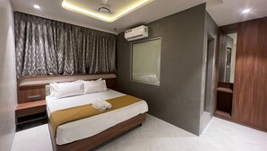 Quarto moderno com cama grande, guarda-roupa embutido e luminária no teto.
