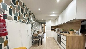 Cozinha moderna com armários brancos, bancada de madeira e um espaço de refeições com uma cadeira amarela.