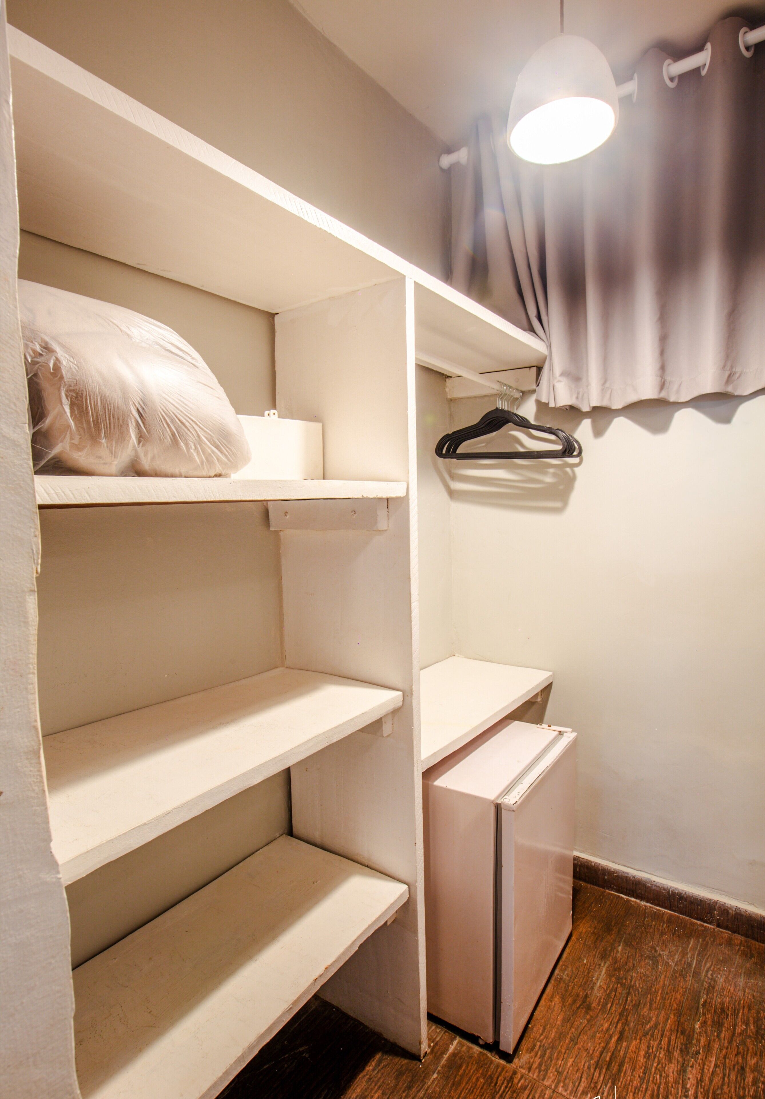 Um closet amplo com prateleiras abertas, cabideiro e uma pequena mesa.