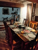 Uma sala de jantar com uma mesa de madeira posta para uma refeição, cercada por cadeiras.