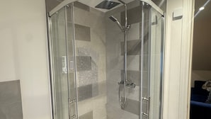 Um banheiro moderno com chuveiro de vidro, pia branca e piso de madeira.