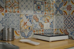 Uma cozinha com painel de azulejos atrás do fogão, apresentando diversos desenhos e cores.