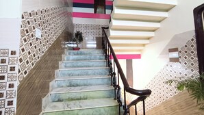 Uma escadaria com paredes estampadas, um corrimão e um vaso de planta.