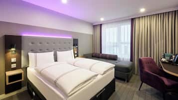 Quarto de hotel com uma cama grande, um sofá, uma escrivaninha e uma cadeira.