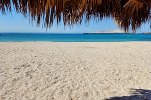 Na praia, areia branca, espreguiçadeiras, toalhas de praia