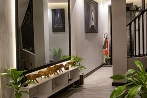 Um corredor com um banco, plantas em vasos, um extintor de incêndio e uma escada.