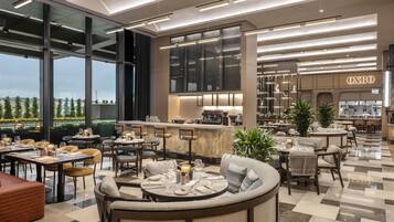 Um lobby de hotel moderno com área de bar, assentos e vista para o exterior.