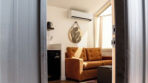 Uma sala de estar moderna com um sofá, uma máquina de café e um objeto decorativo na parede.