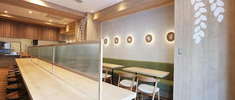 Interior moderno de restaurante com um balcão de madeira comprido, várias áreas de estar e uma parede decorativa com padrões circulares.
