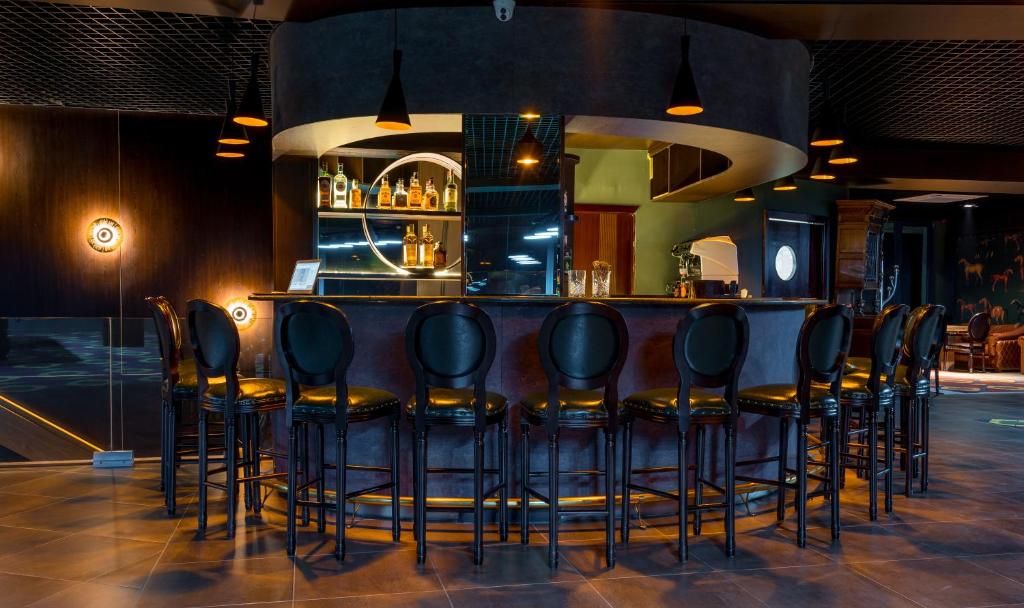 Uma área de bar com balcão circular, vários bancos e iluminação pendente.