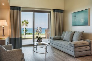 Uma sala de estar moderna com sofá, poltrona e mesa de centro, vista para o oceano e um quadro na parede.