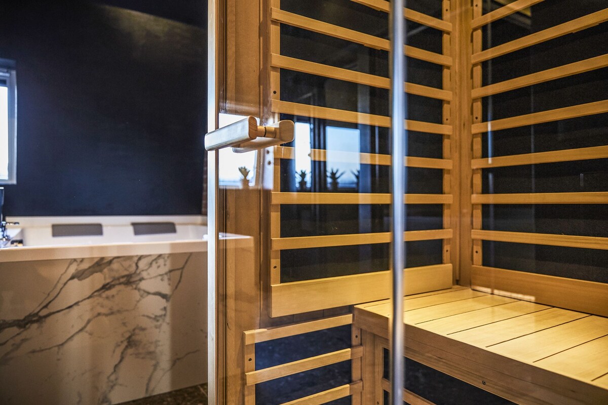 Sala de sauna com bancos de madeira e porta de vidro.