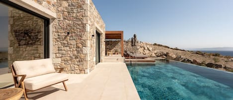 Um edifício de pedra com piscina, sofá e mesa.