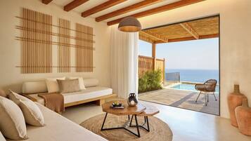 Uma sala de estar moderna com um sofá, uma mesa de centro e vista para o oceano através de uma porta de vidro deslizante.