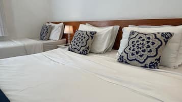 Quarto de hotel com uma cama grande, duas mesas de cabeceira e uma cabeceira de madeira.
