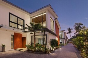 Uma casa moderna de dois andares, com janelas amplas, telhado plano e entrada com calçada.