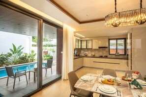 Uma cozinha moderna com área de jantar, piscina e vista para o verde.