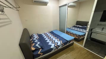 Quarto pequeno com cama, armário e espelho.