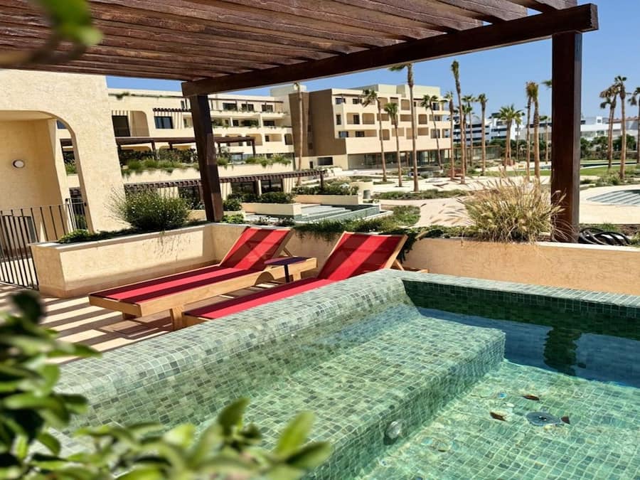 Uma área de piscina com espreguiçadeiras e um deck revestido de azulejos.
