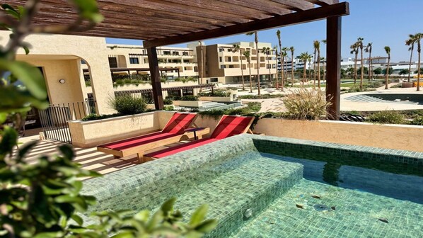 Uma área de piscina com espreguiçadeiras e um deck revestido de azulejos.