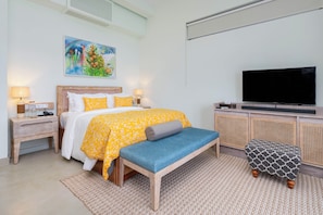Quarto com cama, mesas de cabeceira, um banco e televisão.