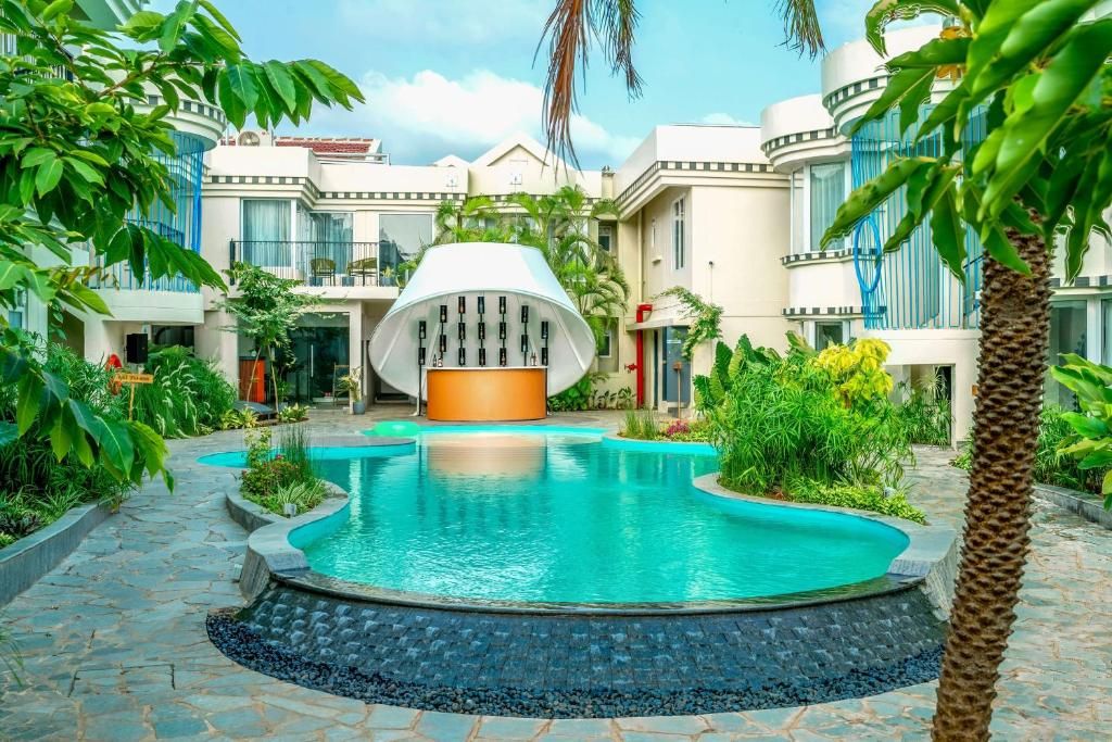 Área de piscina com um edifício moderno ao fundo, cercada por vegetação exuberante.