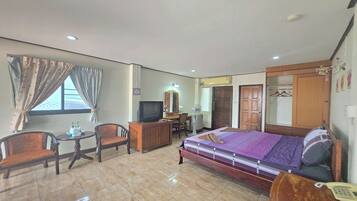 Quarto de hotel com cama, escrivaninha, cadeira, televisão e armário.
