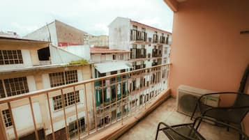 Varanda com vista para edifícios altos, uma cadeira e um aparelho de ar condicionado.