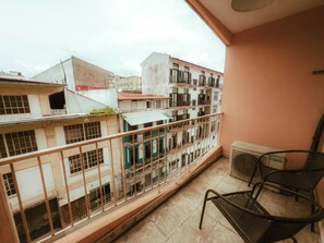 Varanda com vista para edifícios altos, uma cadeira e um aparelho de ar condicionado.
