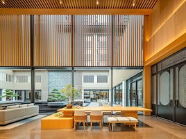 Um lobby moderno com balcão de recepção, área de estar e grandes janelas.
